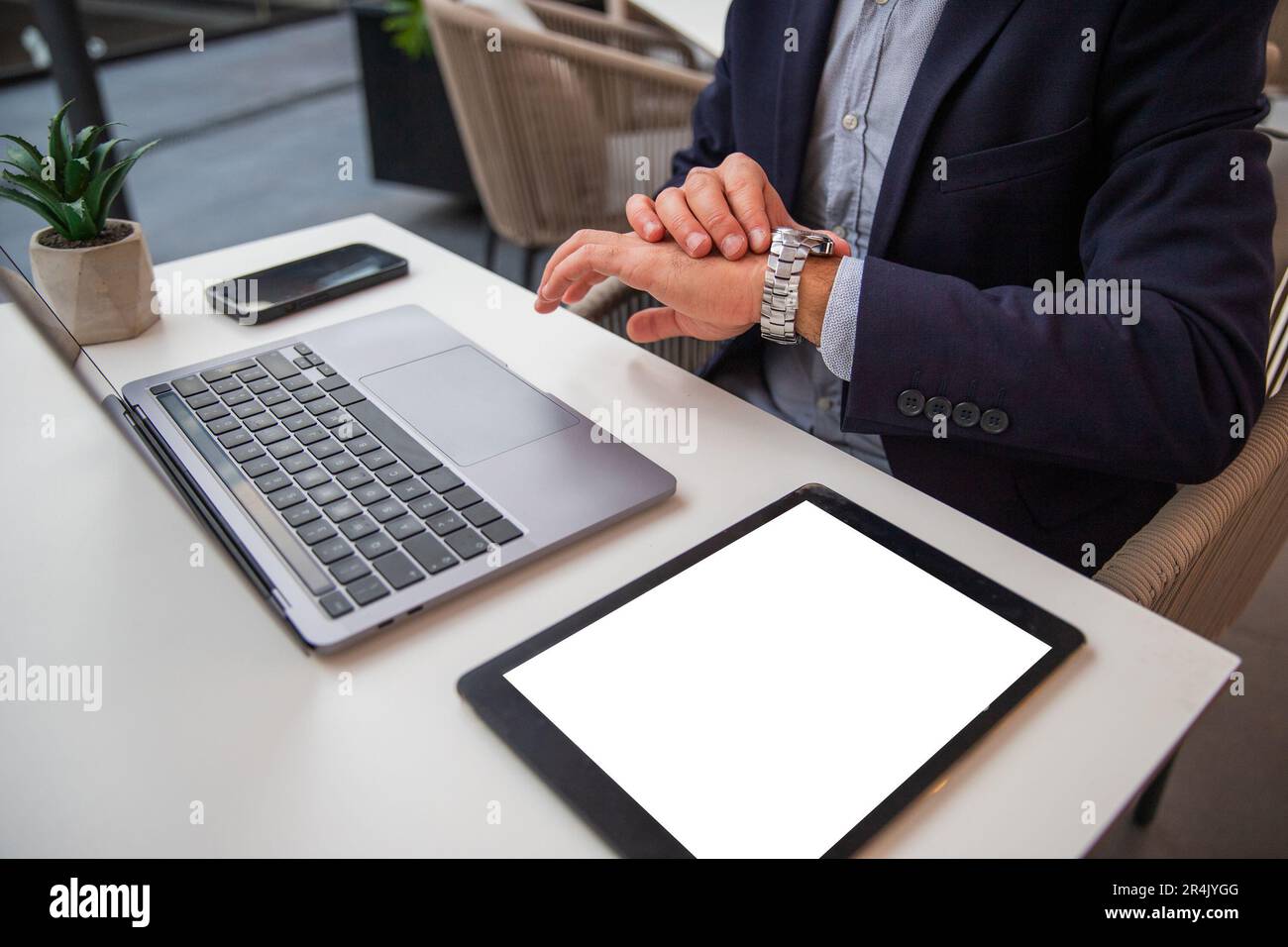 Businessman's desk, he checks the time on his watch, blank tablet ...
