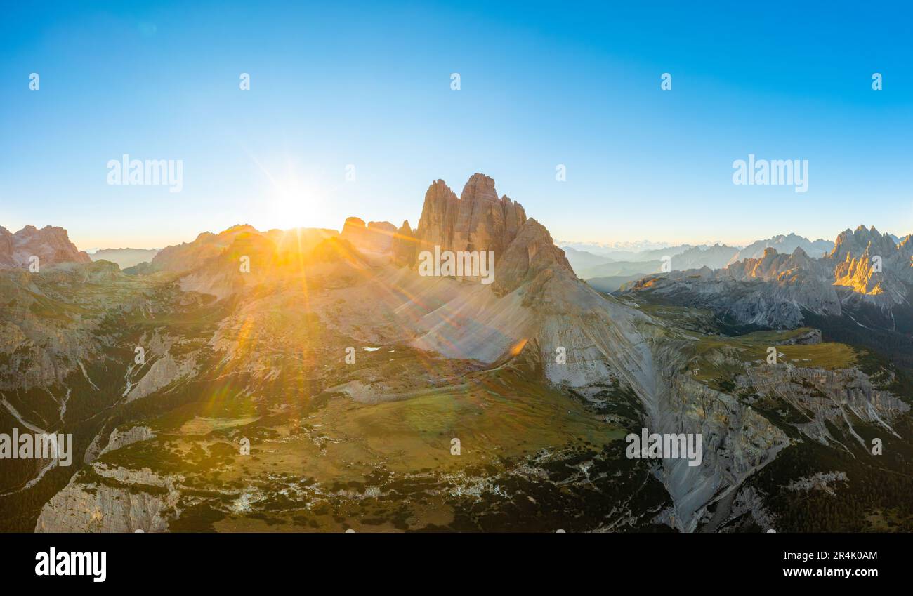 Sun rises from behind peak of rocky mountain silhouette. Landscape of ...