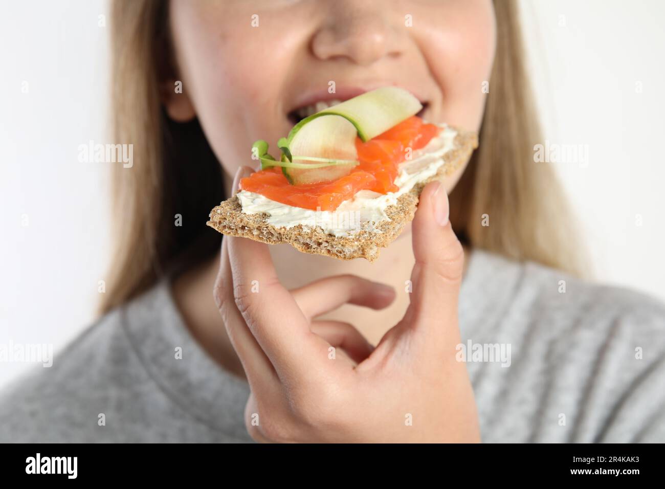 Woman eating fresh rye crispbread with cream cheese, salmon and ...