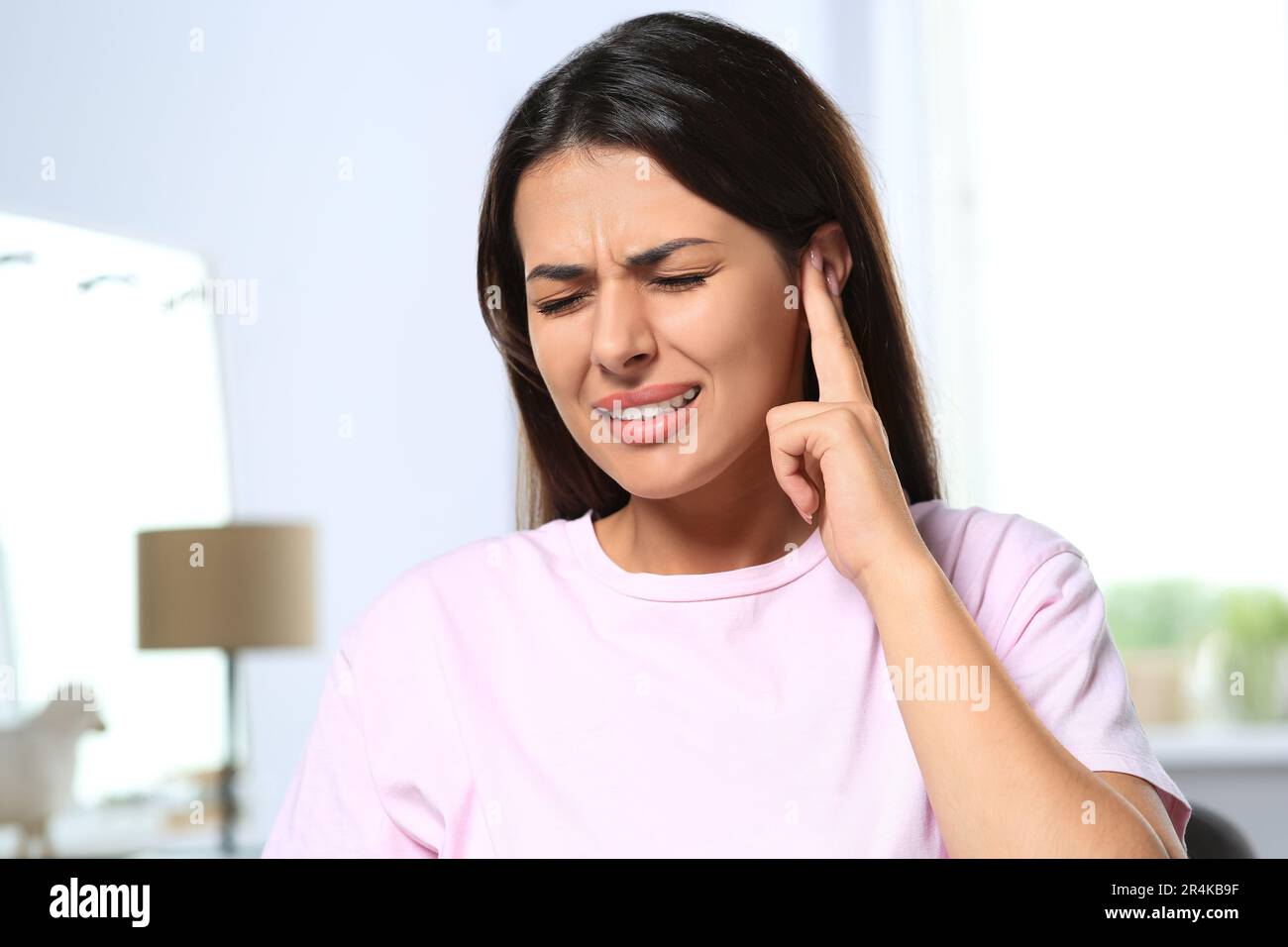 Young woman suffering from ear pain indoors Stock Photo - Alamy