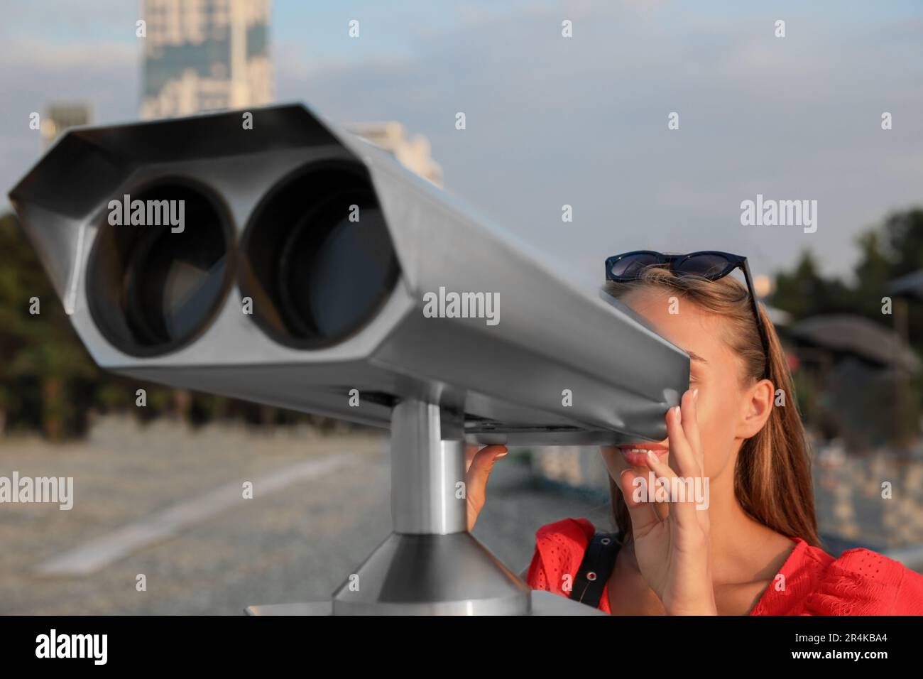 Young woman looking through tourist viewing machine at observation deck ...