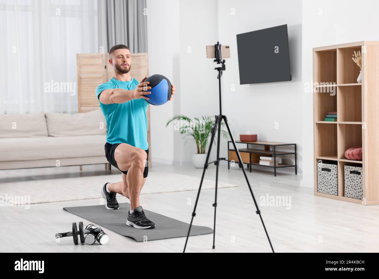 Trainer with ball streaming online workout on phone at home Stock Photo ...