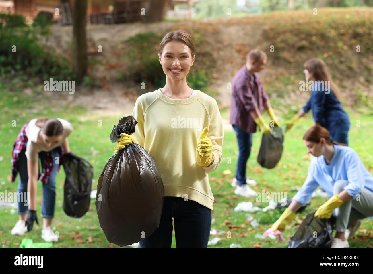 Young woman with plastic bag showing thumb up and group of people ...