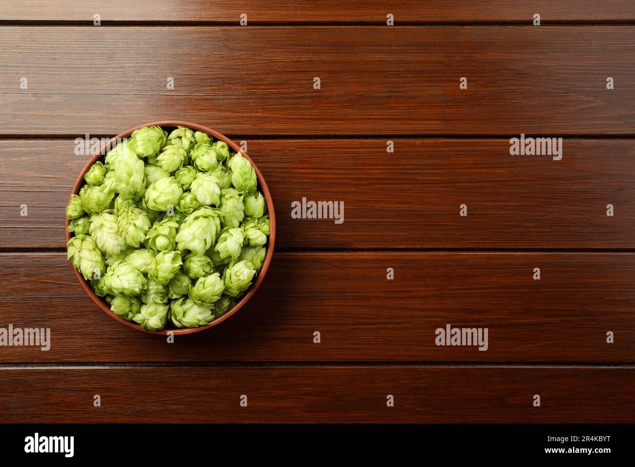 Bowl with fresh green hops on wooden table, top view. Space for text ...