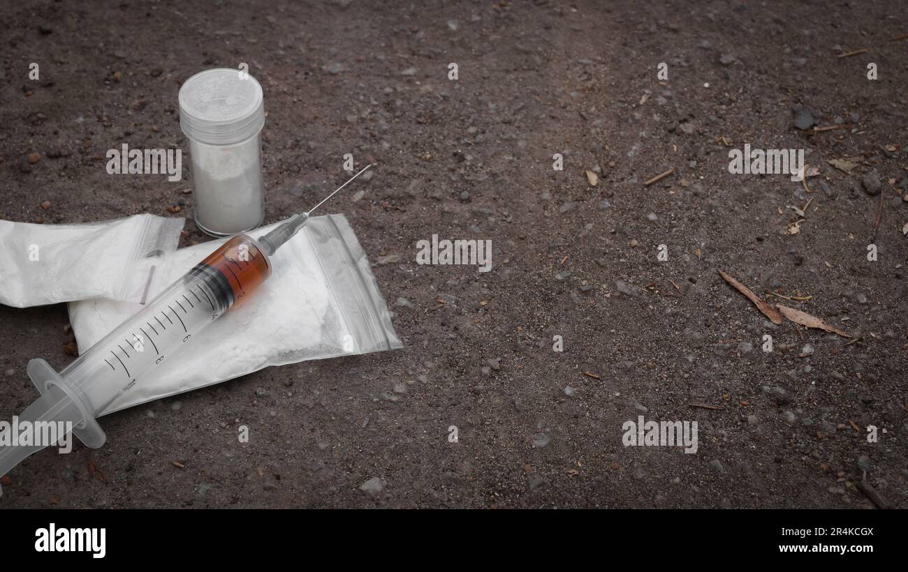 Plastic bags, container with powder and syringe on asphalt, space for ...