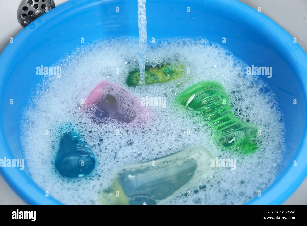 Light blue basin with baby bottles under stream of water in sink ...