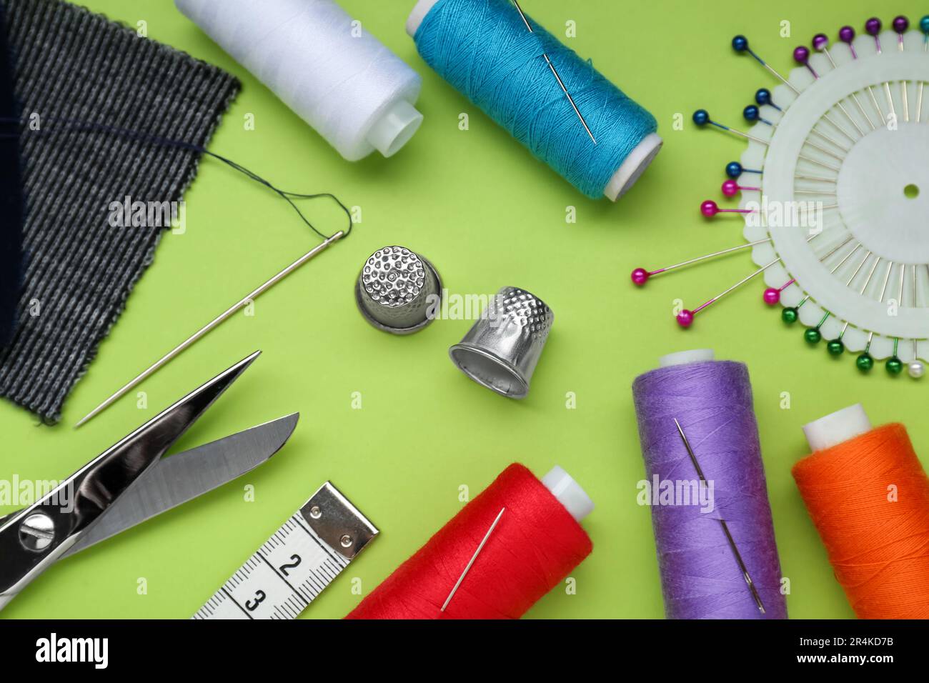 Flat lay composition with thimbles and different sewing tools on green ...