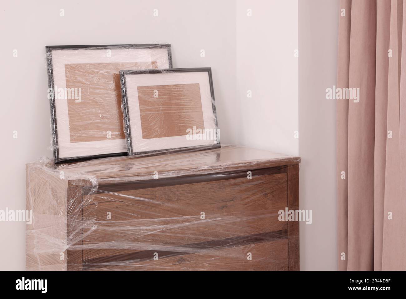 Picture frames and chest of drawers wrapped in stretch film indoors ...