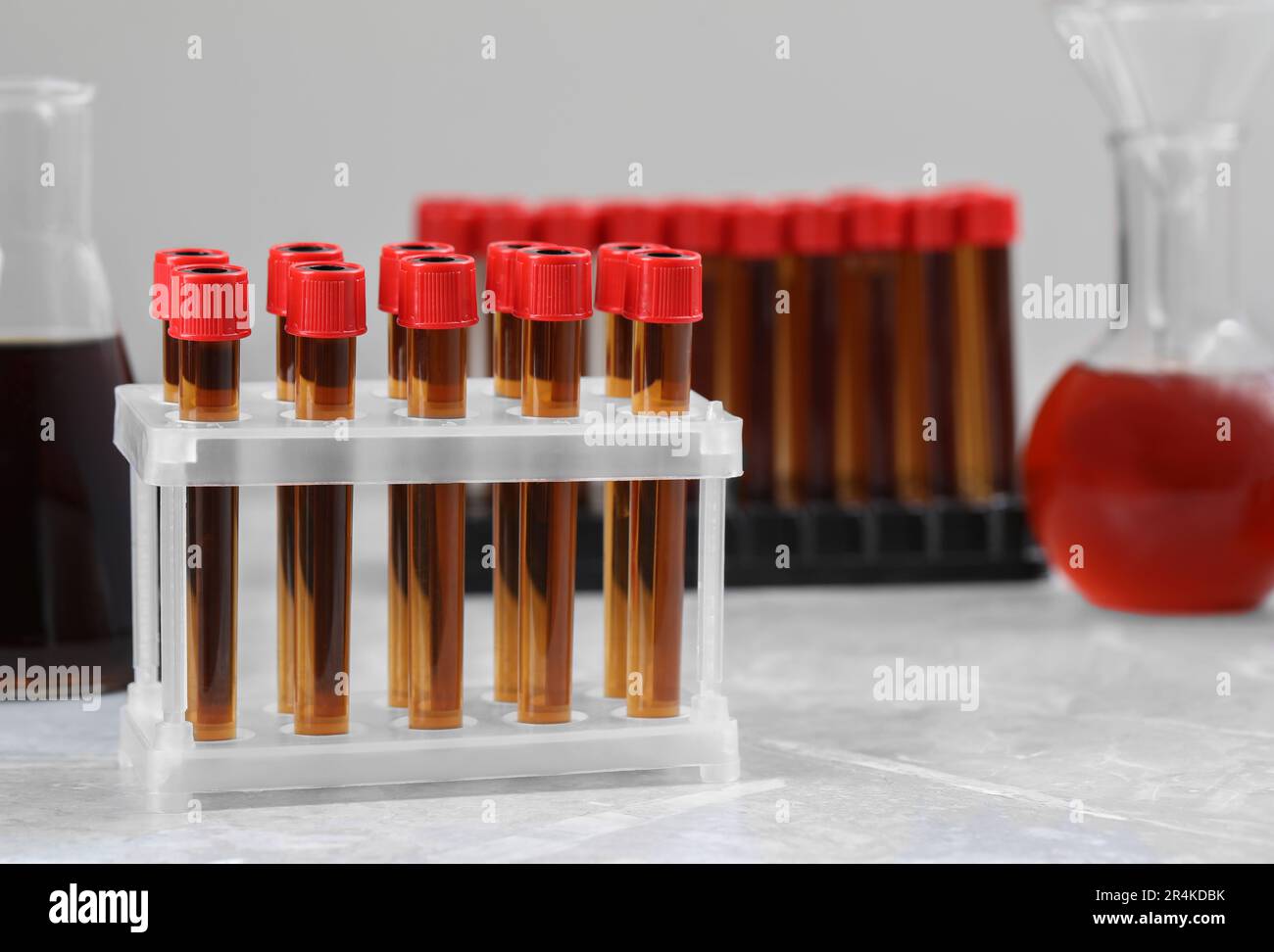 Different laboratory glassware with brown liquids on white table. Space ...
