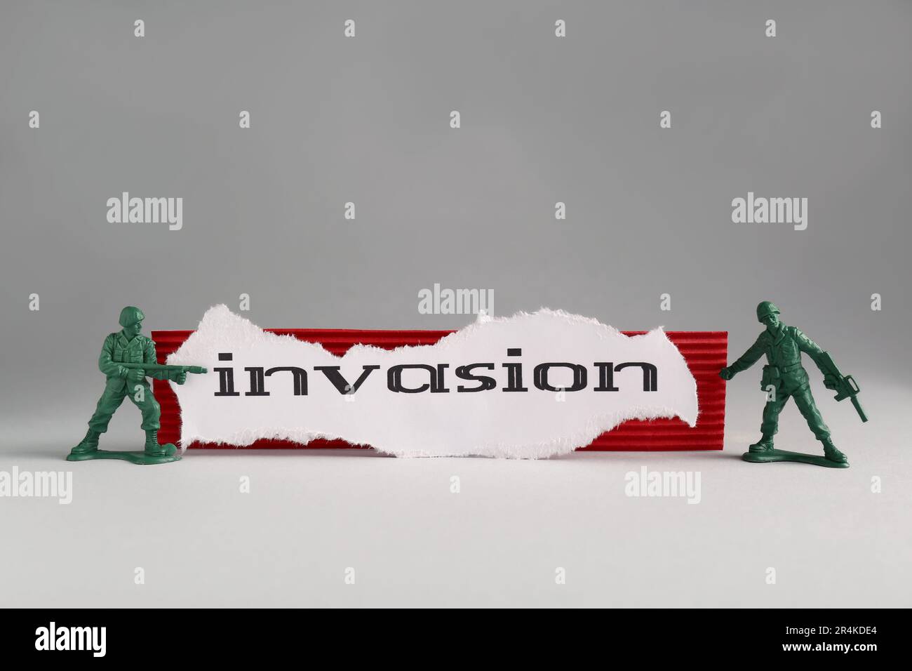 Paper with word Invasion and toy soldiers on light grey background ...