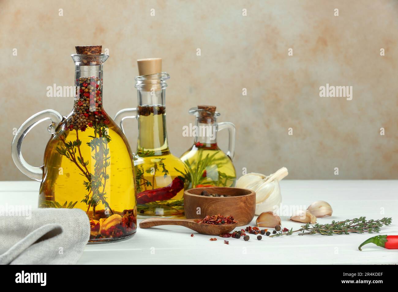 Cooking oil with different spices and herbs in jugs on white wooden ...