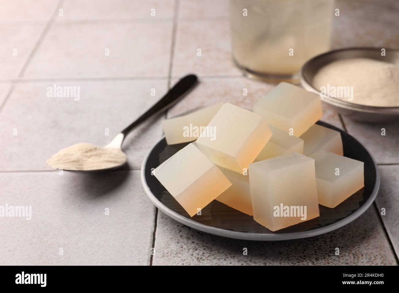 Agar-agar jelly cubes and powder on tiled surface, closeup Stock Photo ...
