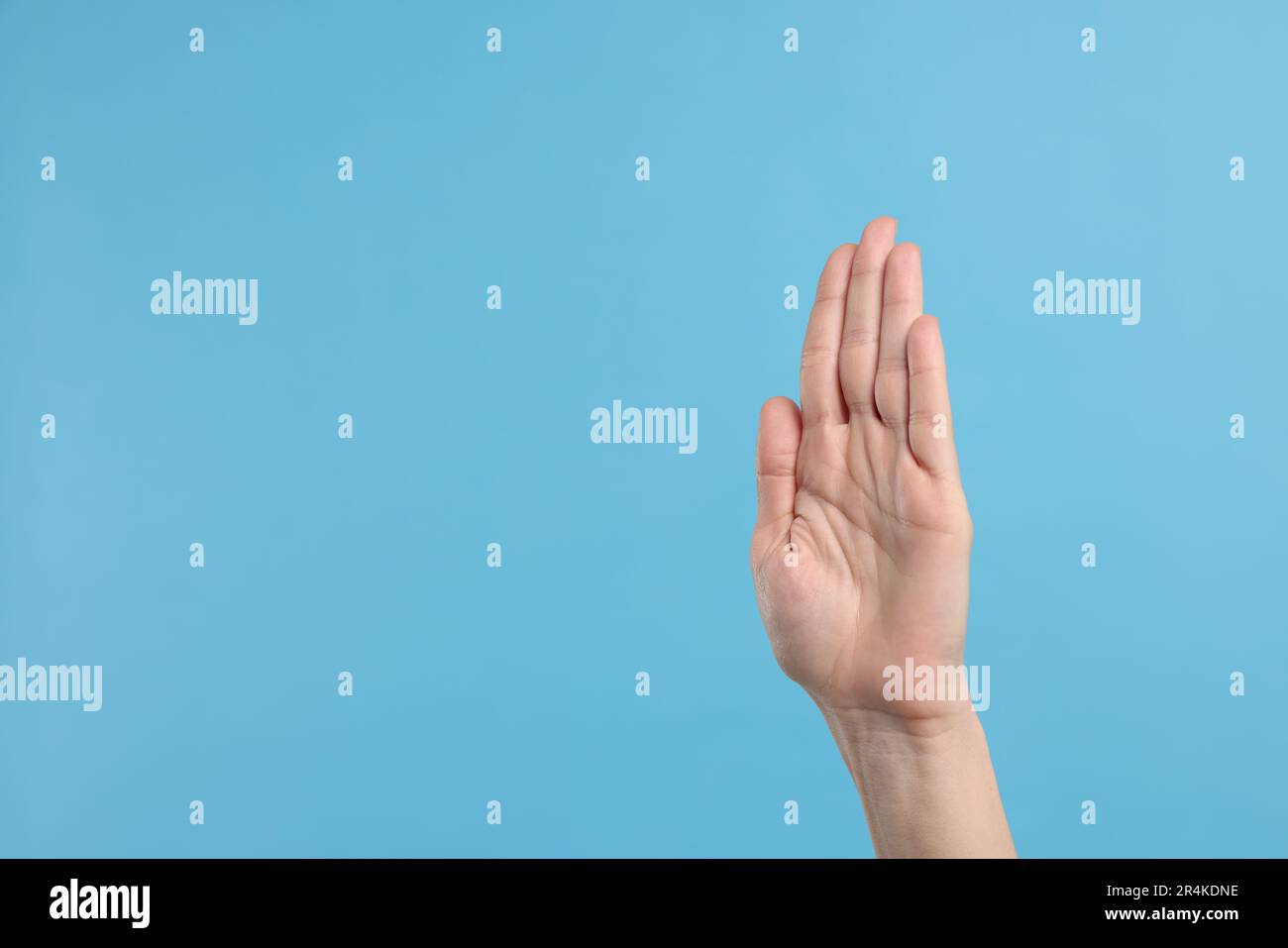 Woman giving high five on light blue background, closeup. Space for ...