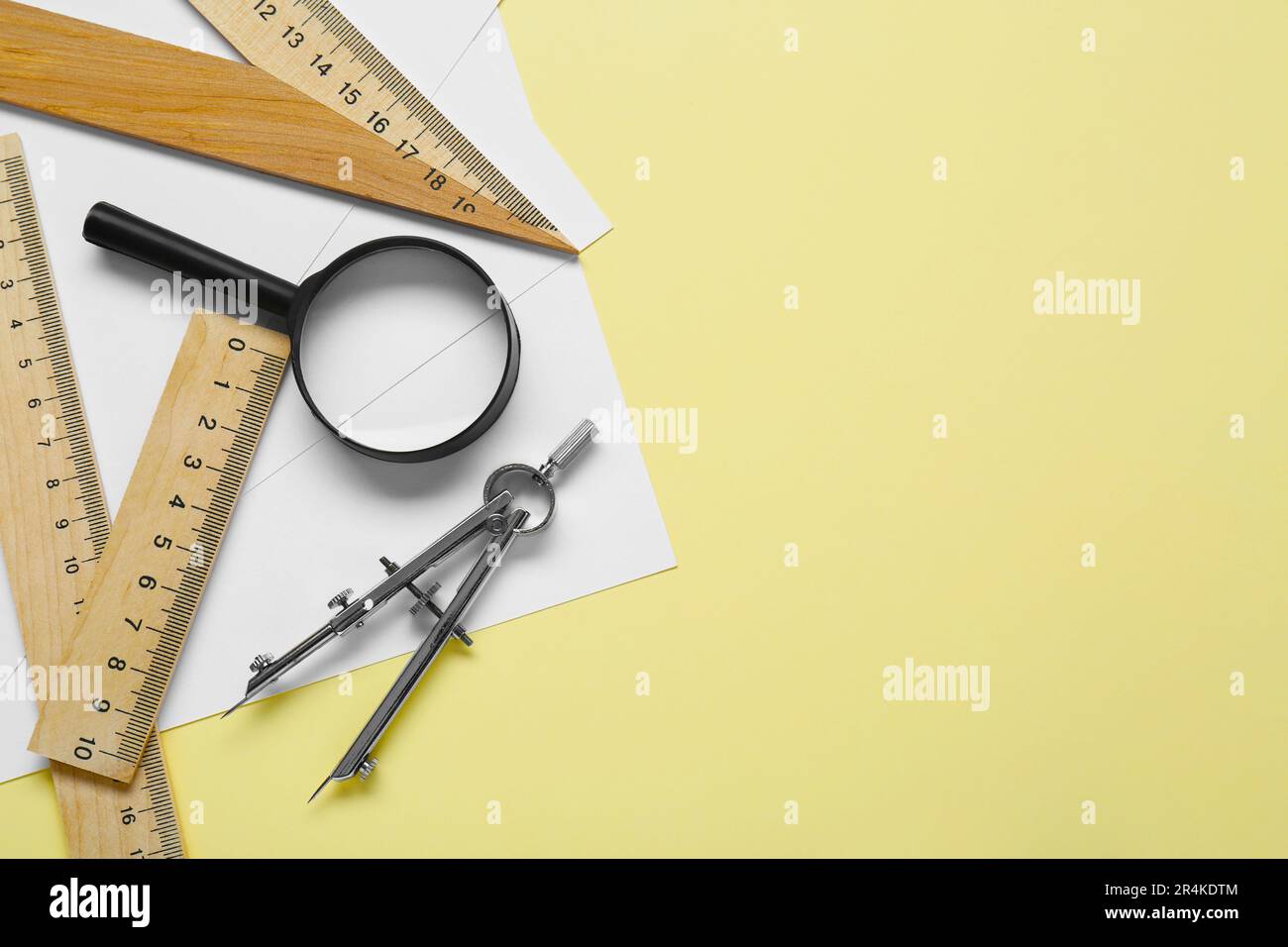 Different rulers, magnifying glass and compass on yellow background ...