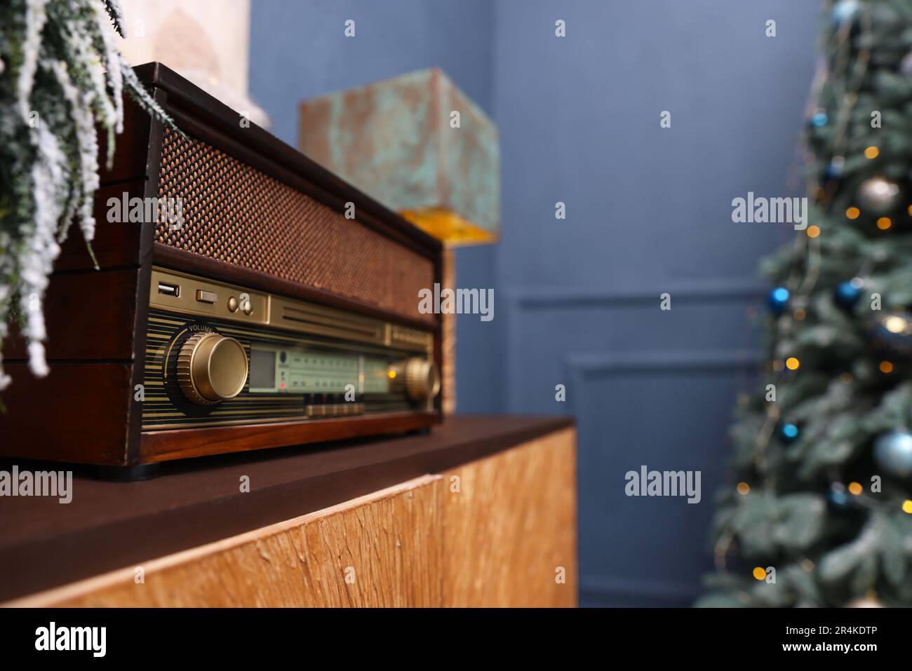 Retro radio on wooden table and Christmas tree in room, space for text ...