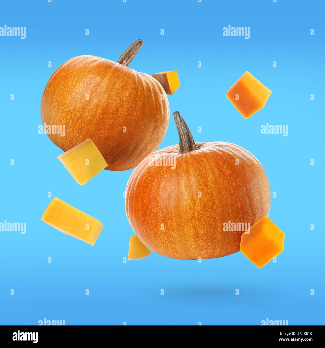 Whole and cut pumpkins falling on light blue background Stock Photo - Alamy