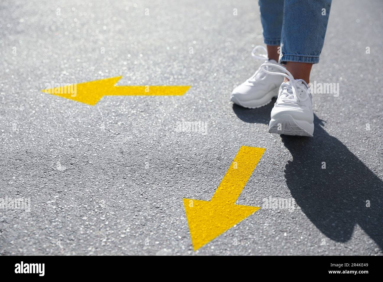 Choice of way. Woman walking to drawn mark on road, closeup. yellow ...