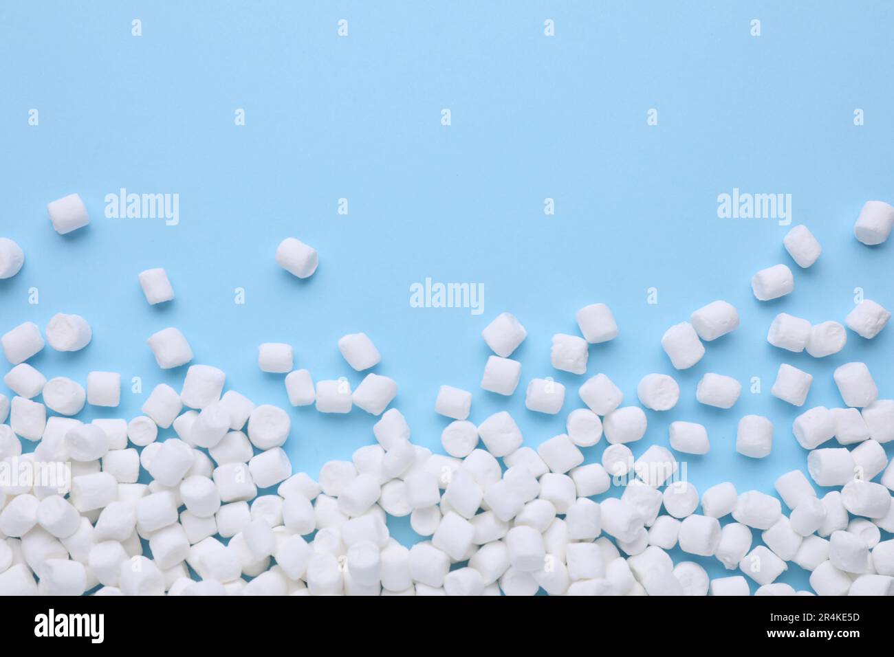 Delicious marshmallows on light blue background, flat lay. Space for ...
