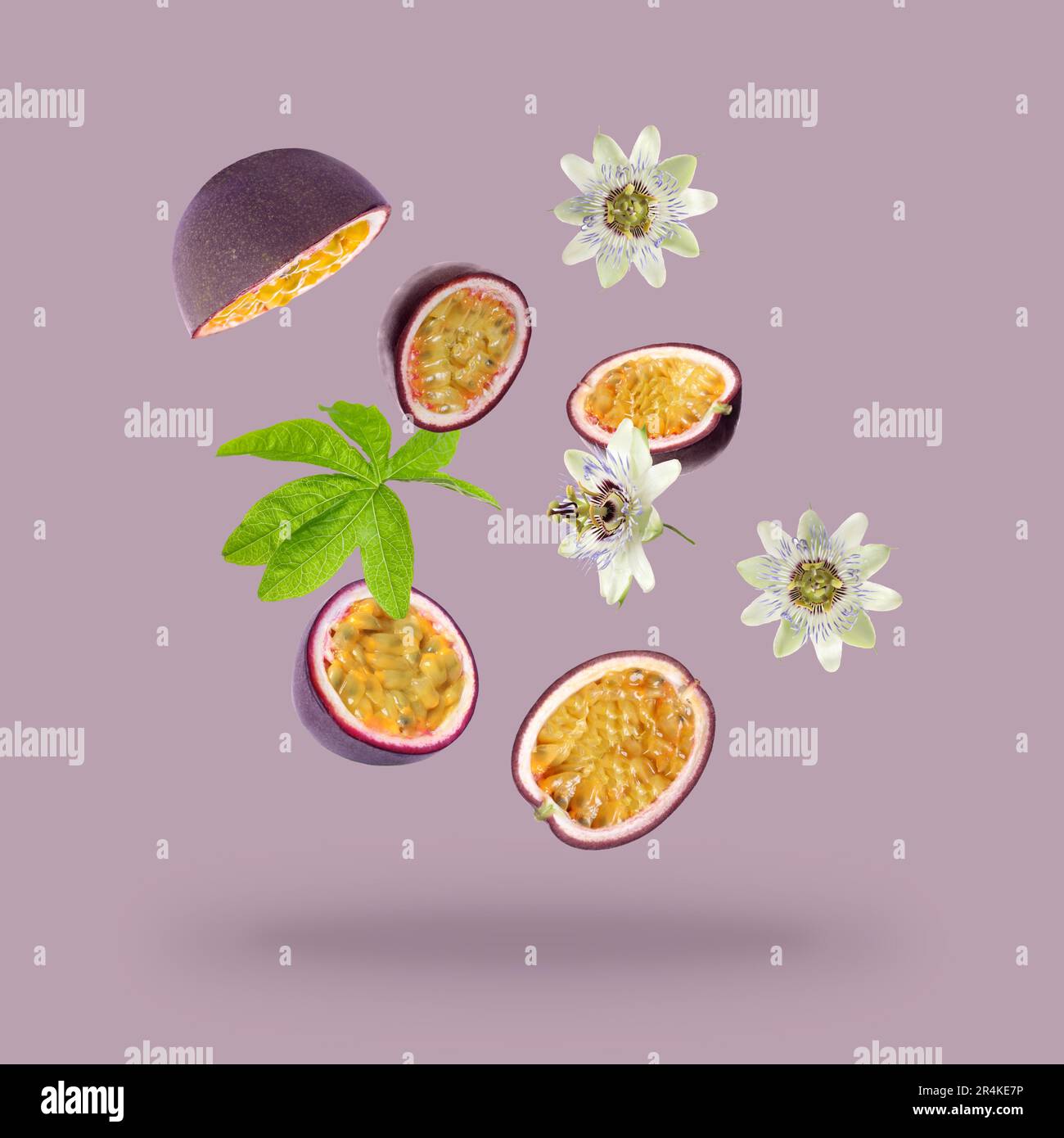 Tasty passion fruits, passiflora leaf and flowers falling on pink ...