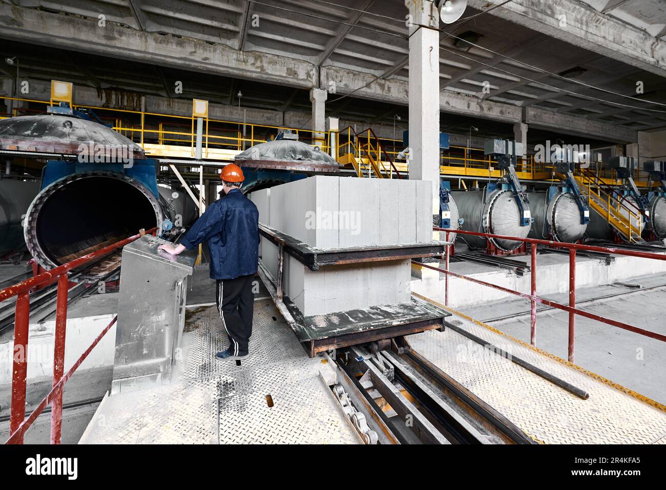 Worker loads raw blocks into open tanks for hardening Stock Photo - Alamy