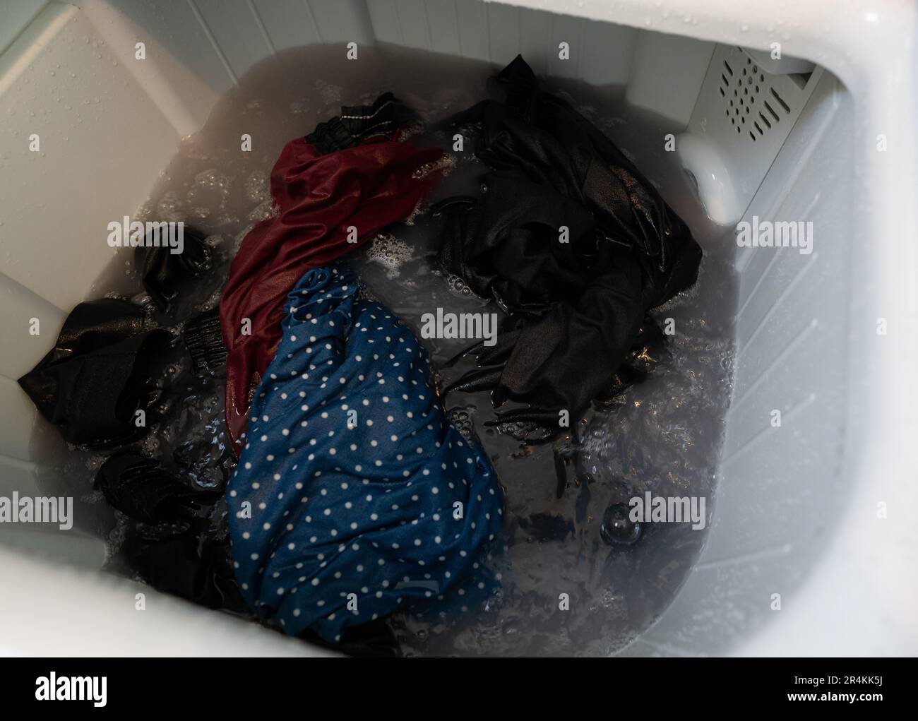 Dirty clothes in top loading washing machine. Clothes with bubble of ...
