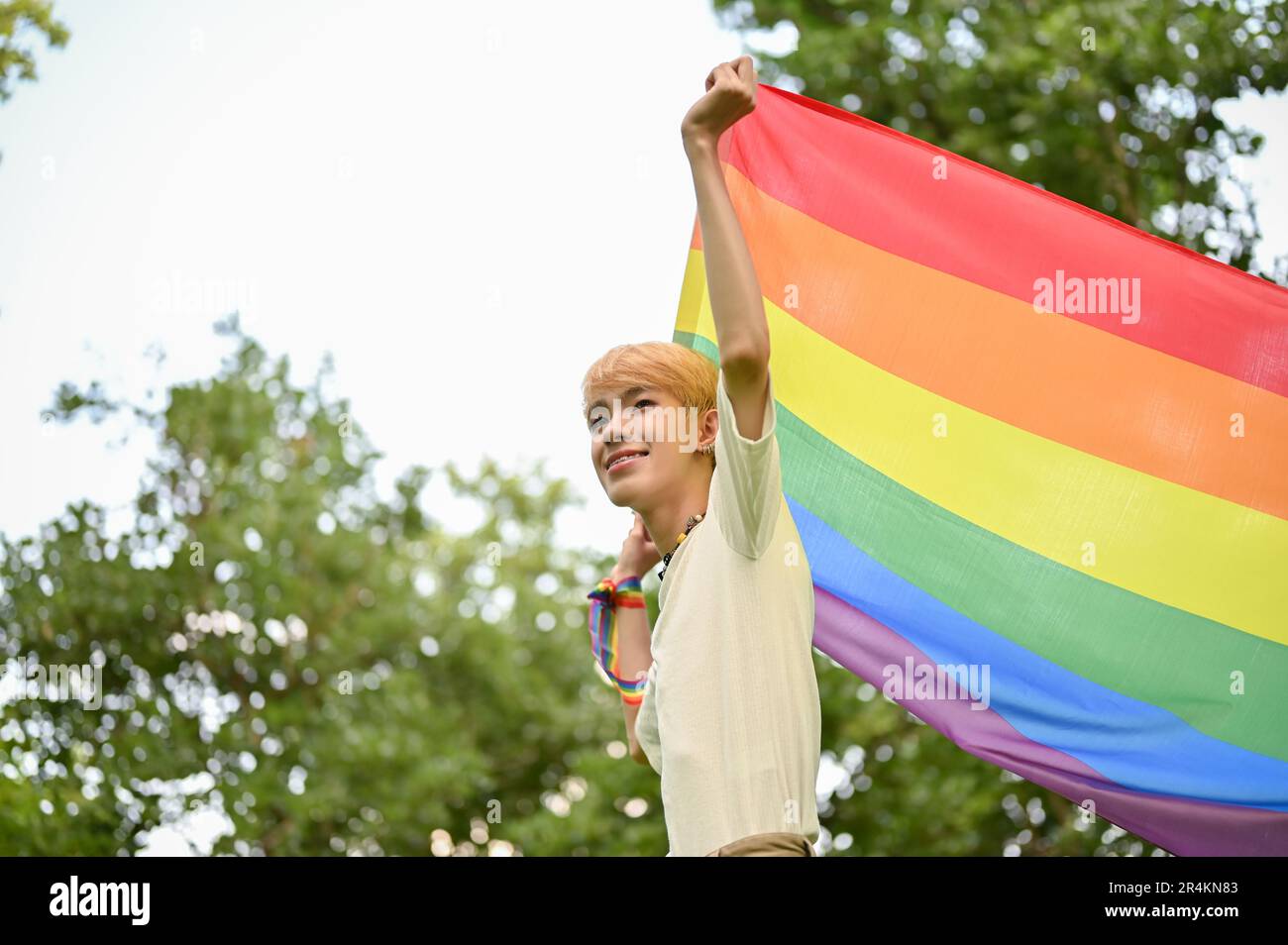 Portrait of an smiling and carefree young Asian gay man with an LGBT ...