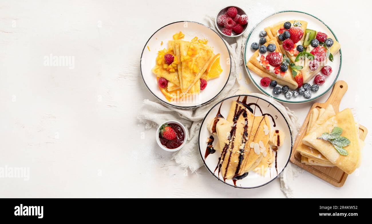 Variety of fresh crepes with chocolate, jam, fruits and berries on ...