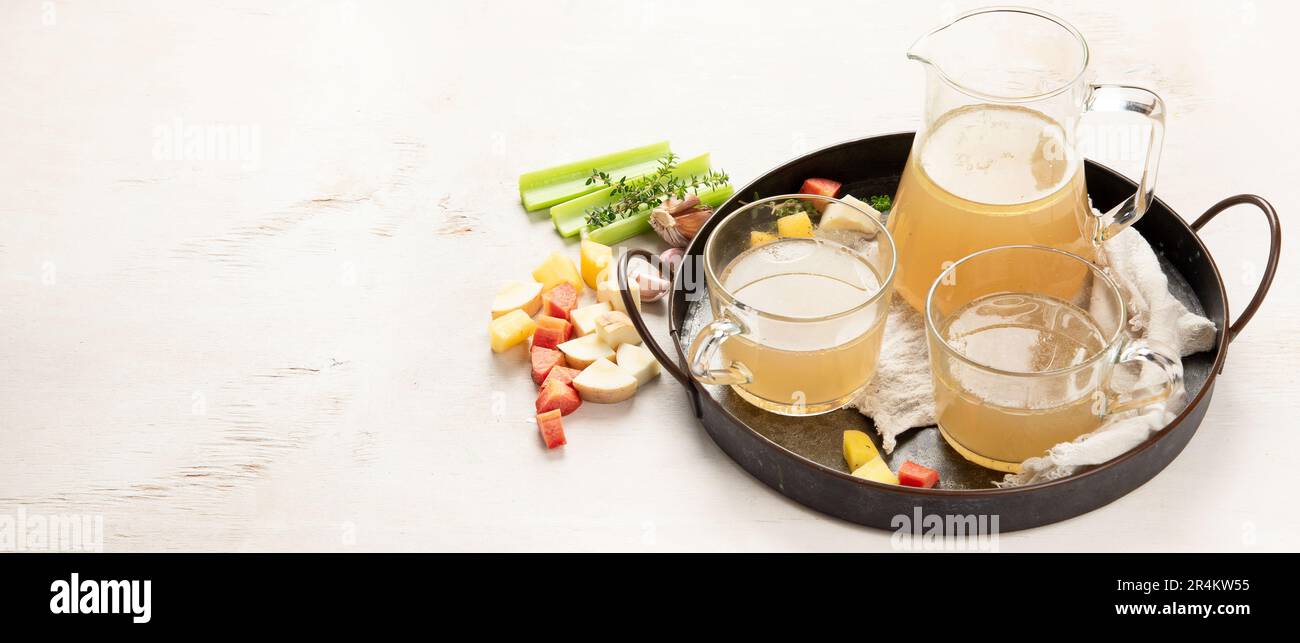 Two cups and glass mug of homemade chicken bone broth on white ...