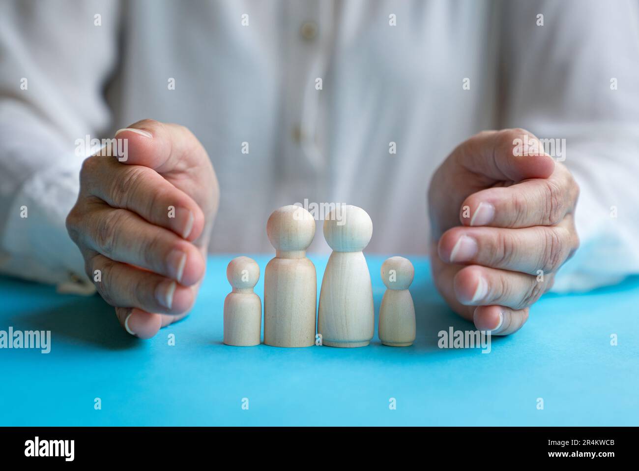 Woman's hands cover over wooden doll family with father, mother ...