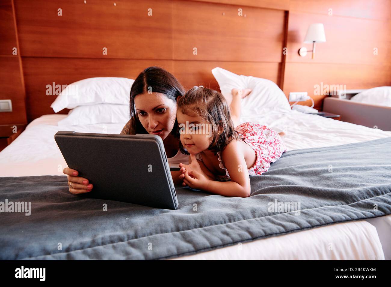 A little girl and her young mother have fun using an iPad on their ...