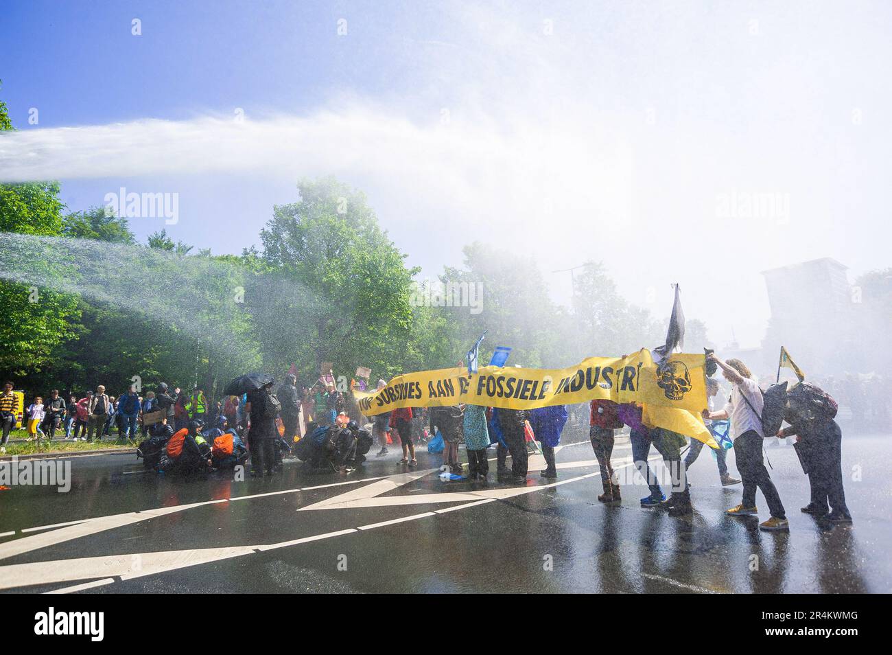 Protesters under a hale of stray from water cannon hold a banner during ...