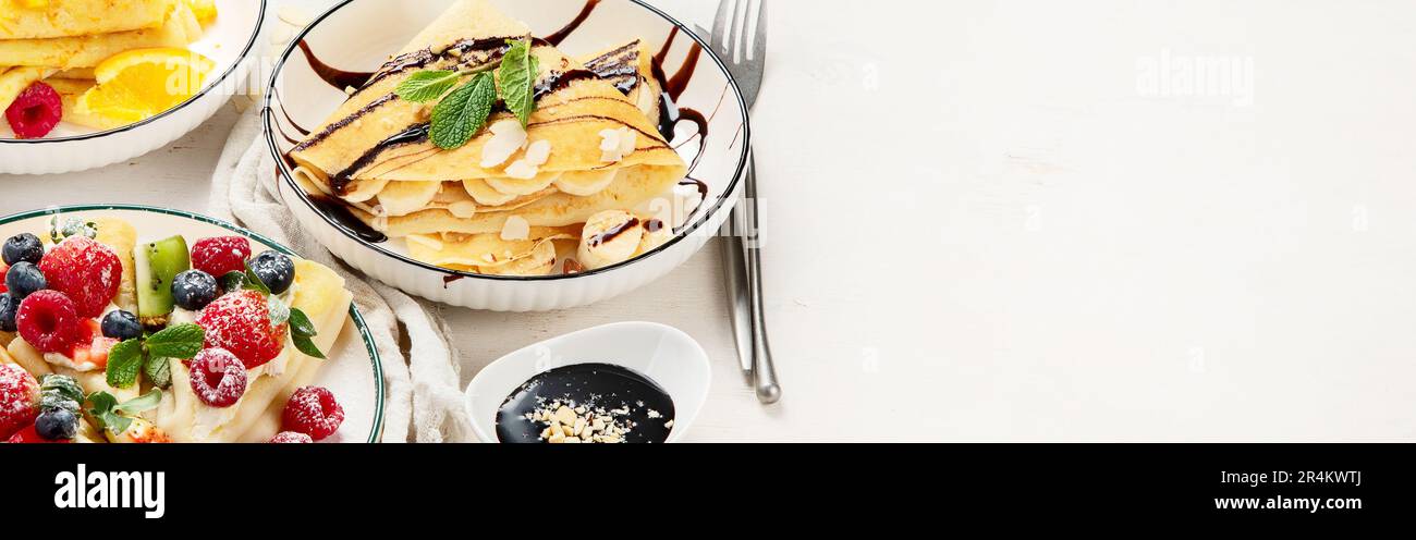 Variety of fresh crepes with chocolate, jam, fruits and berries on ...