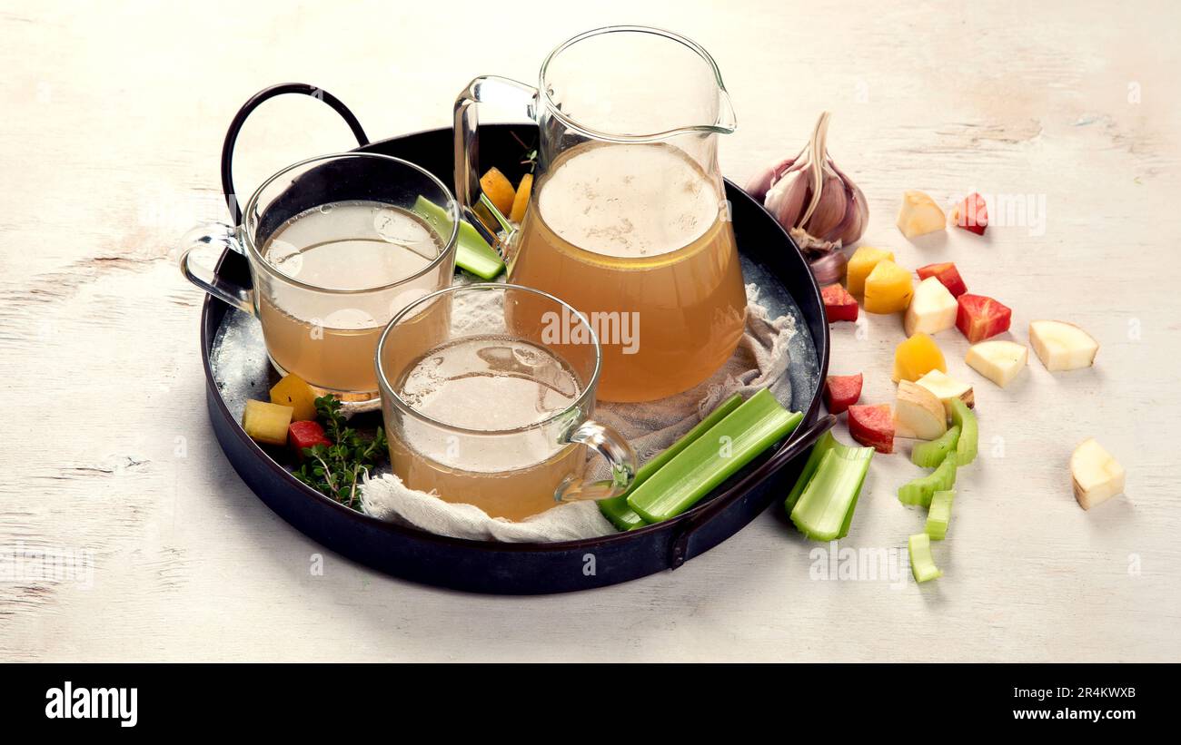 Two cups and glass mug of homemade chicken bone broth on white ...