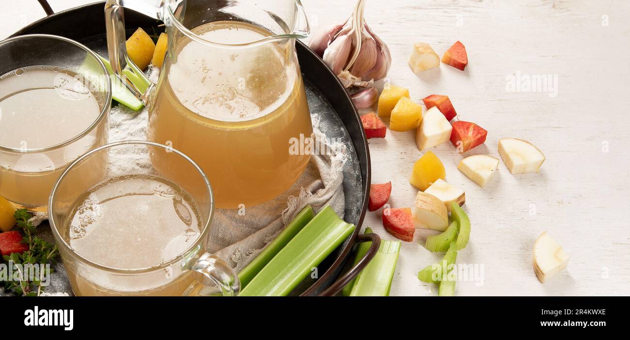 Two cups and glass mug of homemade chicken bone broth on white ...