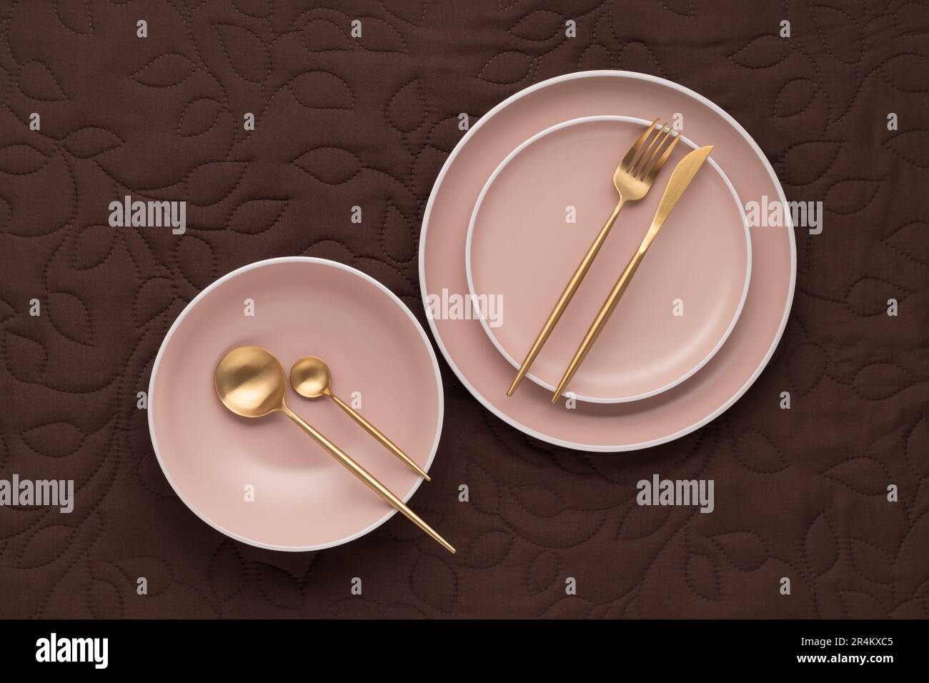 A set of beige plates of different sizes on the table, top view. Golden ...