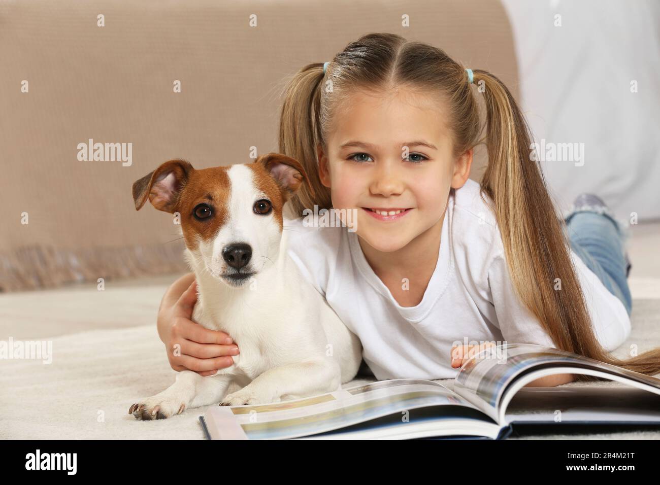 Cute girl reading book on floor with her dog indoors. Adorable pet ...