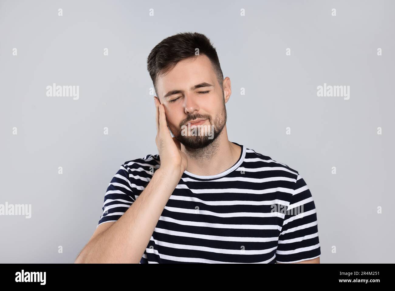 Young man suffering from ear pain on light grey background Stock Photo ...