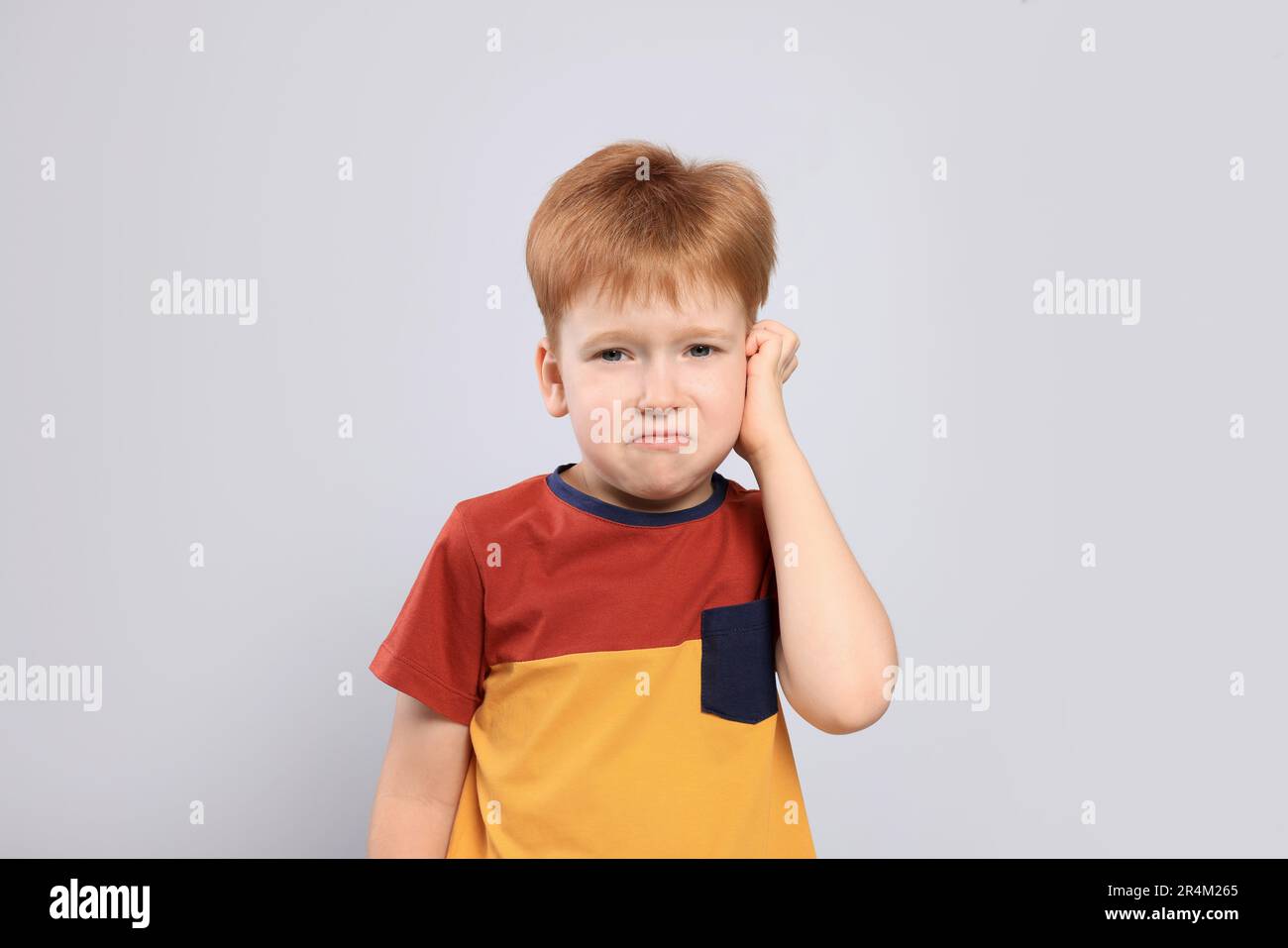 Little boy suffering from ear pain on light grey background Stock Photo ...