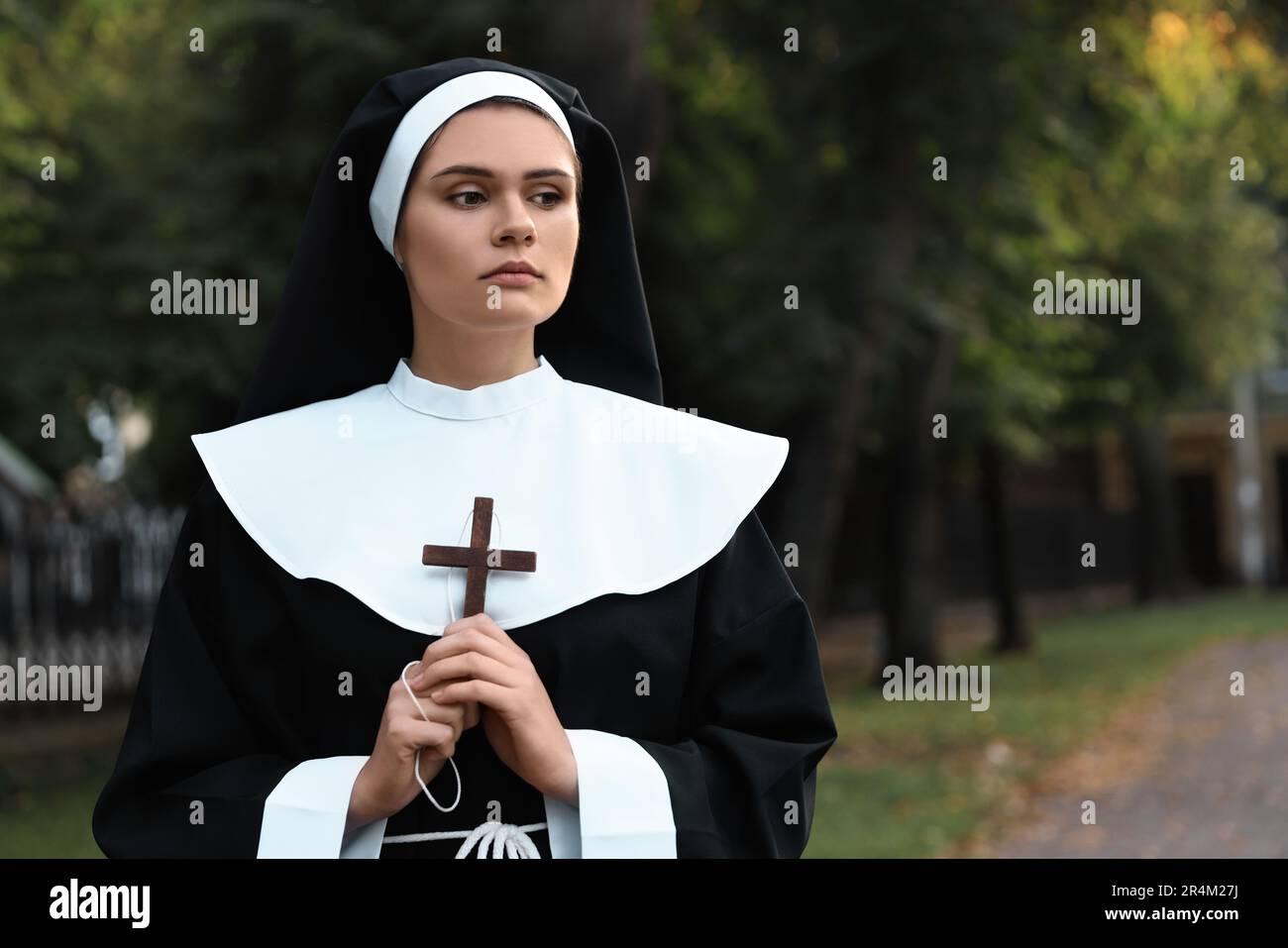 Young nun with Christian cross in park outdoors, space for text Stock ...