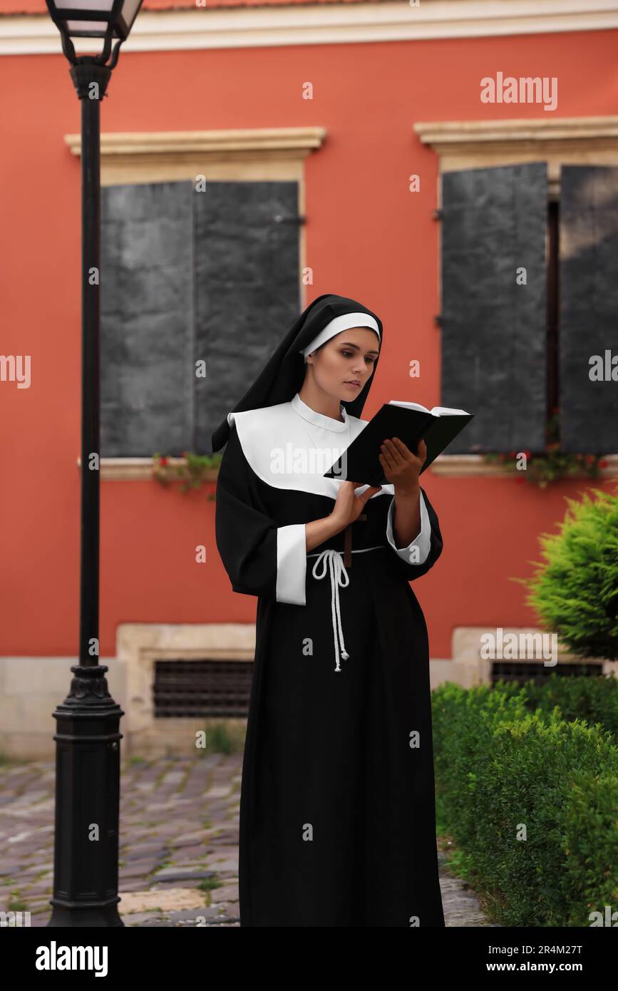 Young nun reading Bible near building outdoors Stock Photo - Alamy