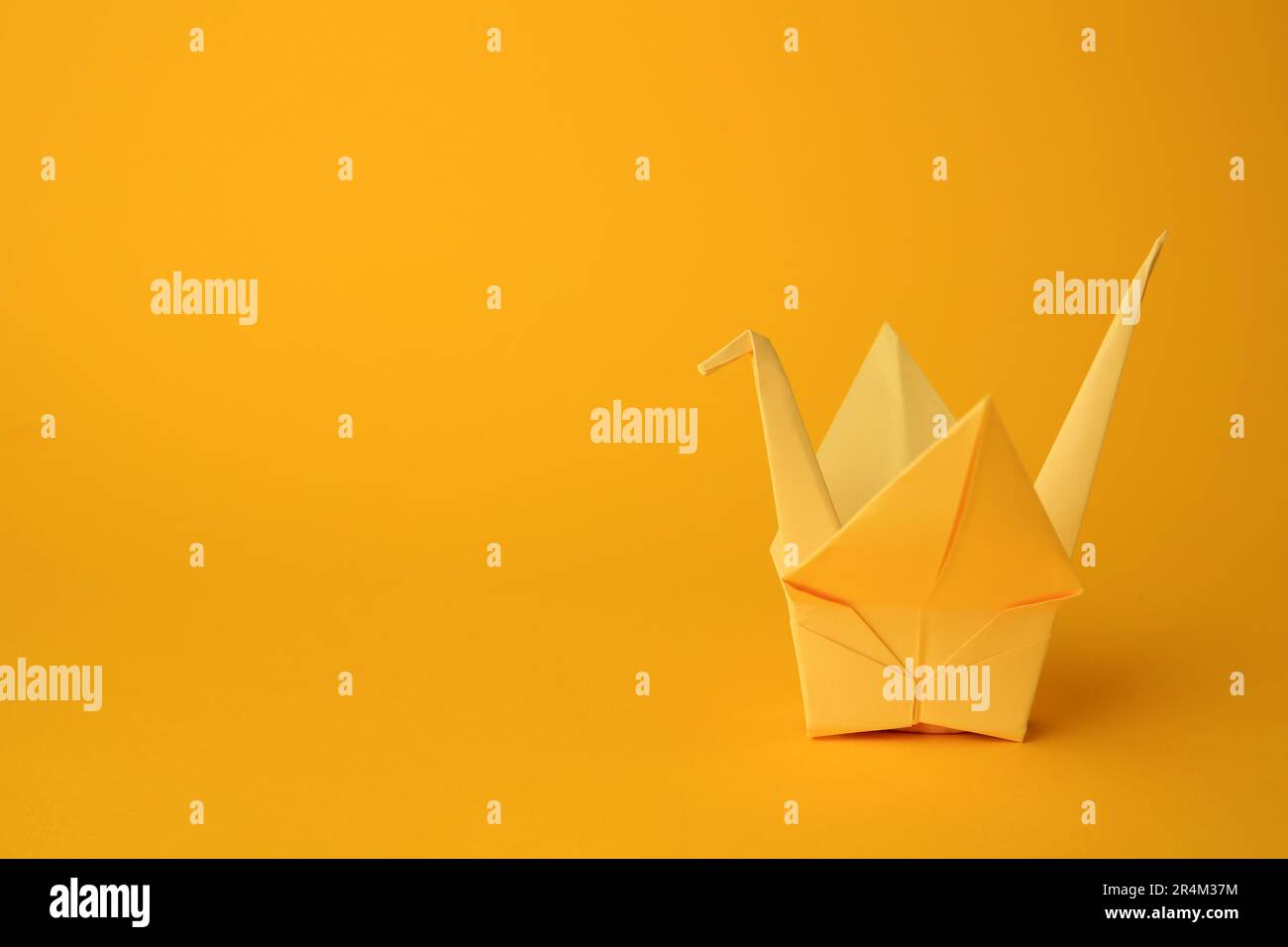 Origami art. Beautiful light yellow paper crane on orange background ...