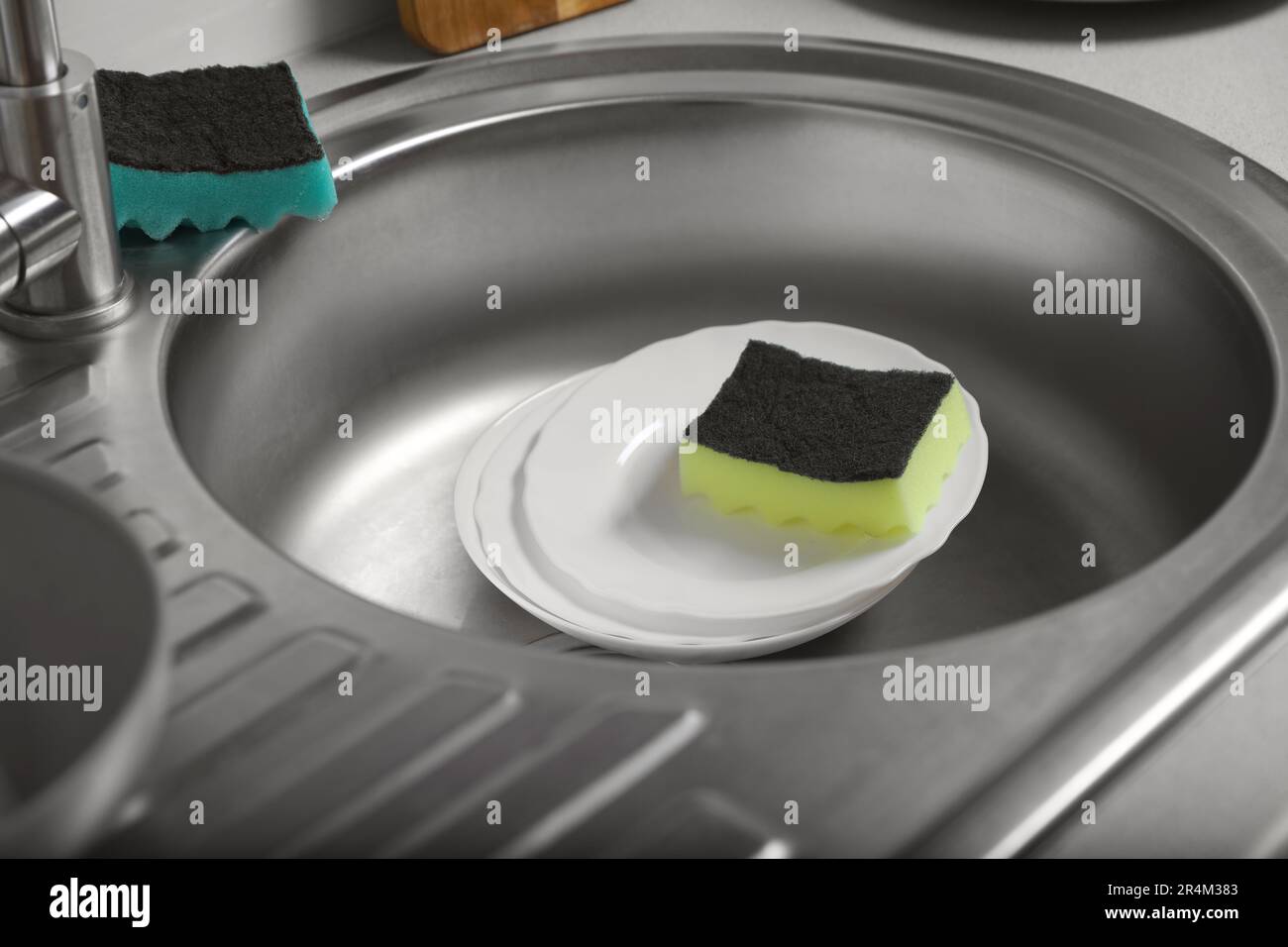 White plates and sponges in kitchen sink. Washing dishes Stock Photo ...