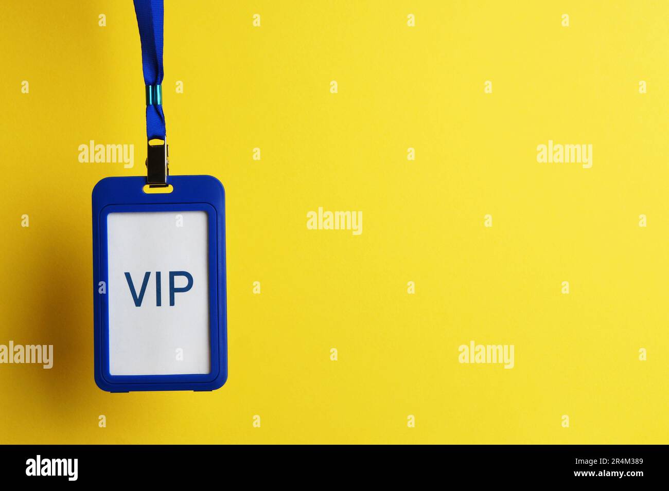 Blue plastic vip badge hanging on yellow background, space for text ...