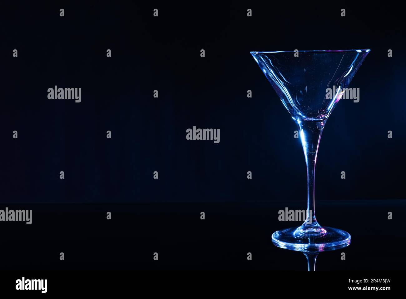 Empty clean martini glass on mirror table against black background ...