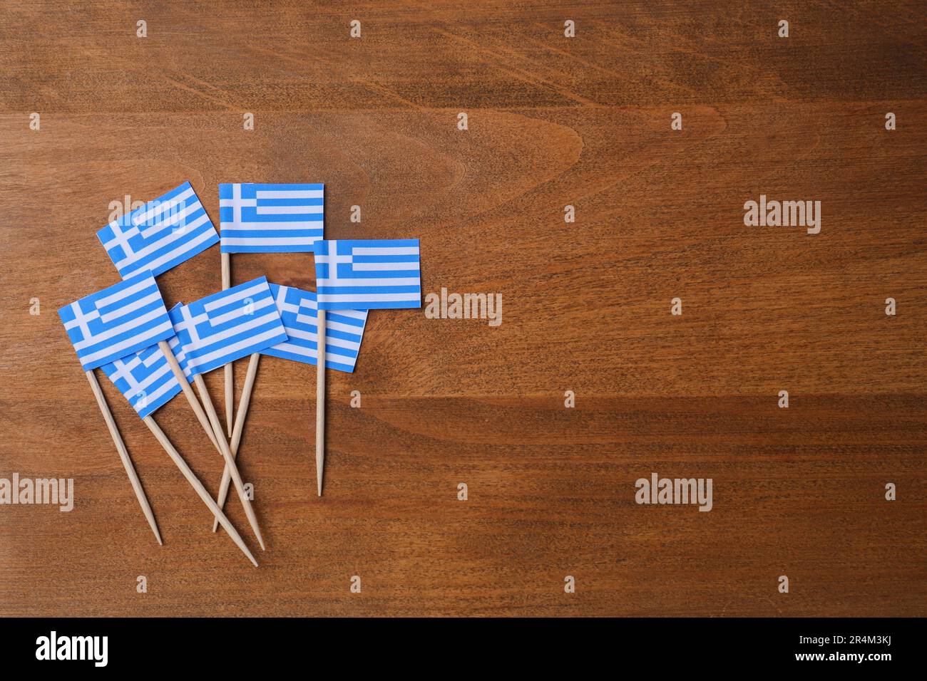 Small paper flags of Greece on wooden table, flat lay. Space for text ...