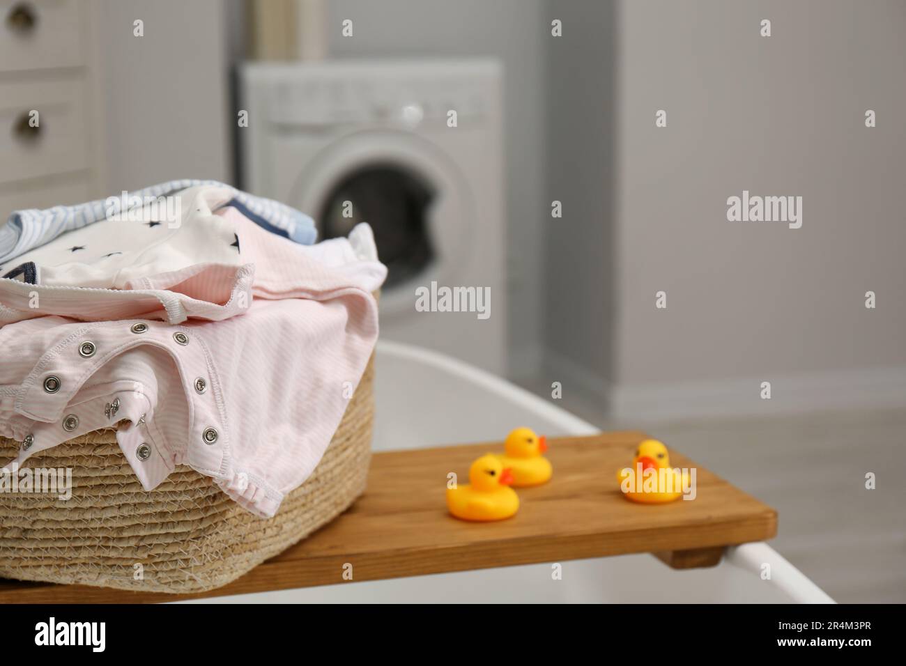 Laundry basket with baby clothes on tub tray in bathroom, closeup ...