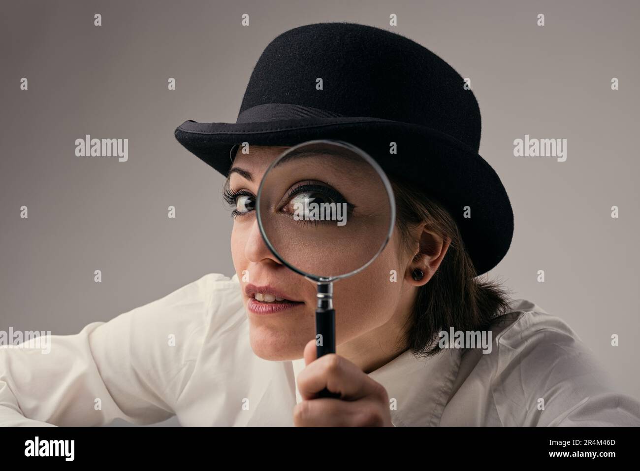 Intense close-up of a woman's eye, peering through a magnifying glass ...