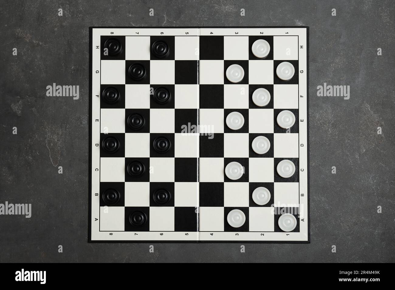 Checkerboard with game pieces on grey table, top view Stock Photo - Alamy
