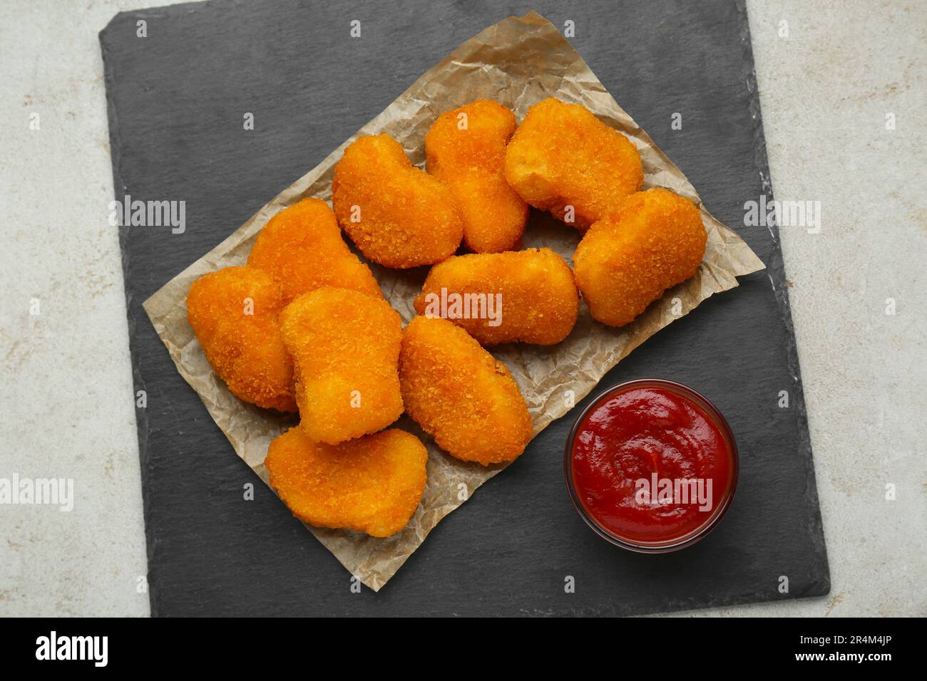 Tasty chicken nuggets with ketchup on light grey textured table, top ...