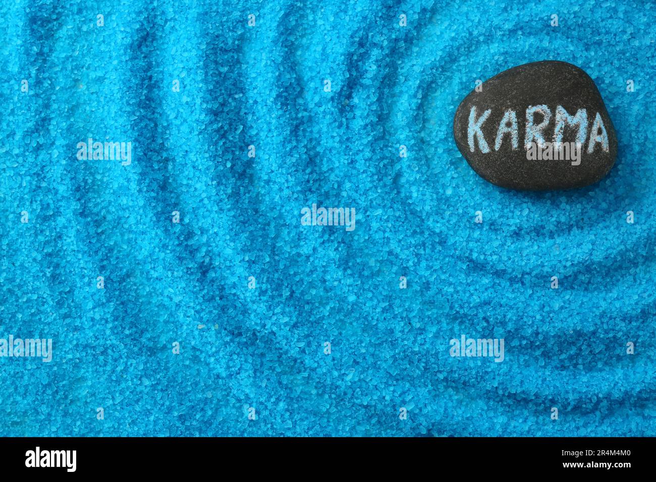 Stone with word Karma on light blue sea salt, top view. Space for text ...